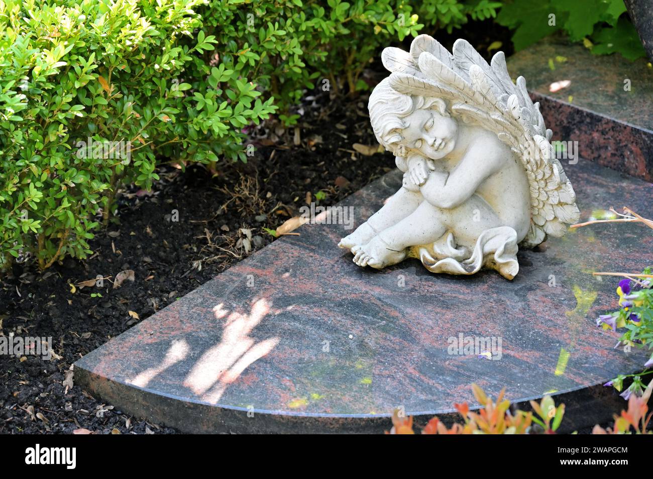 Small white angel sitting on a granite slab as a grave decoration Stock ...