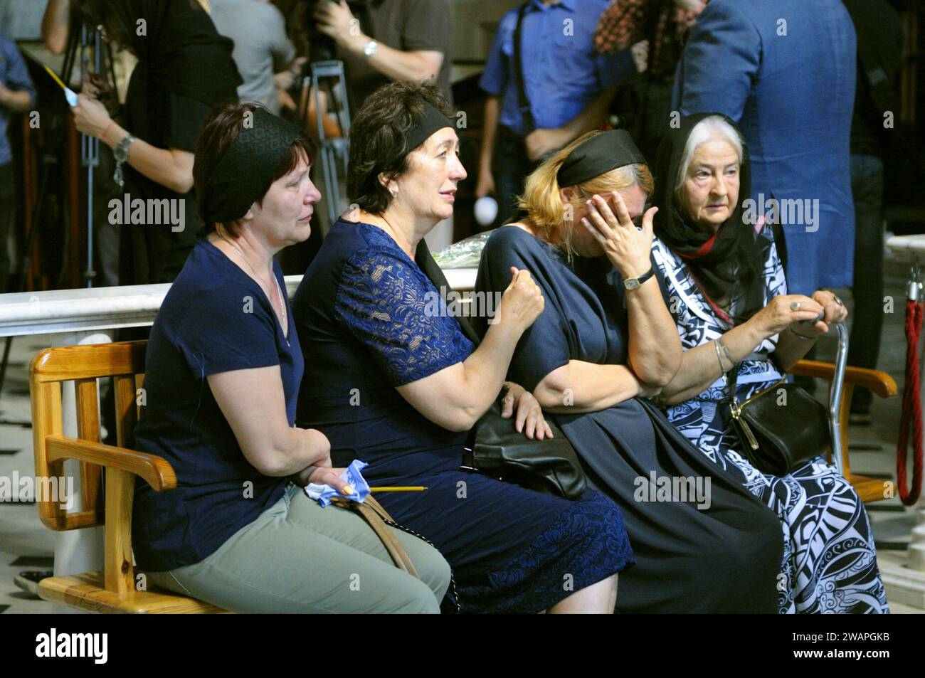 Burial service in a church: relatives of a late sitting on a bench ...