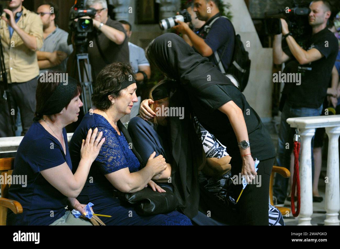 Burial service in a church: relatives of a late sitting on a bench ...