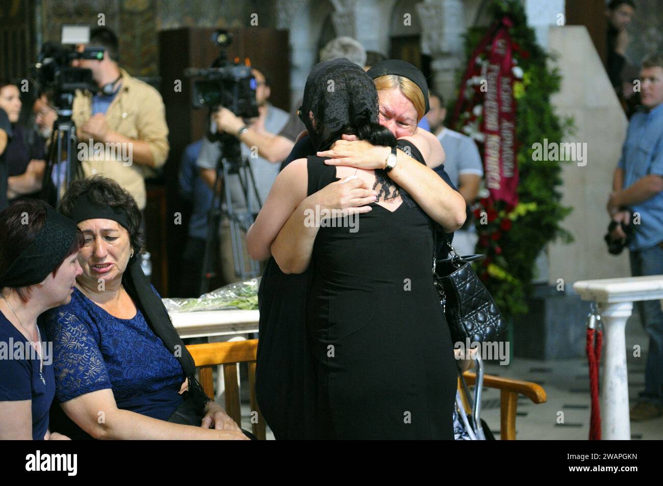 Burial service in a church: relatives of a late sitting on a bench ...