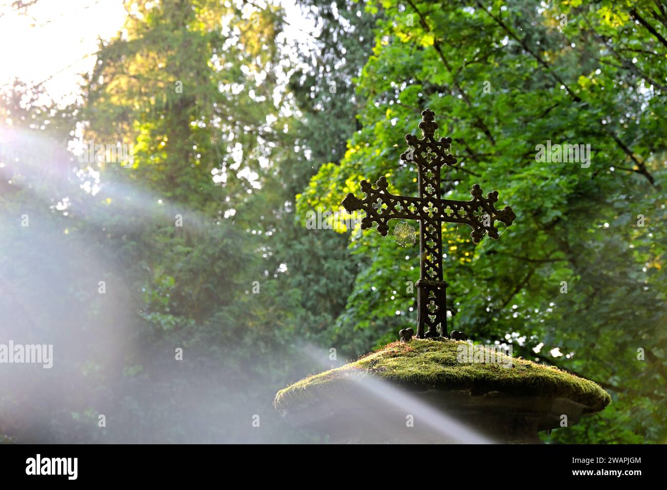 Old metal cross on mossy pillar with light shining from the side Stock ...