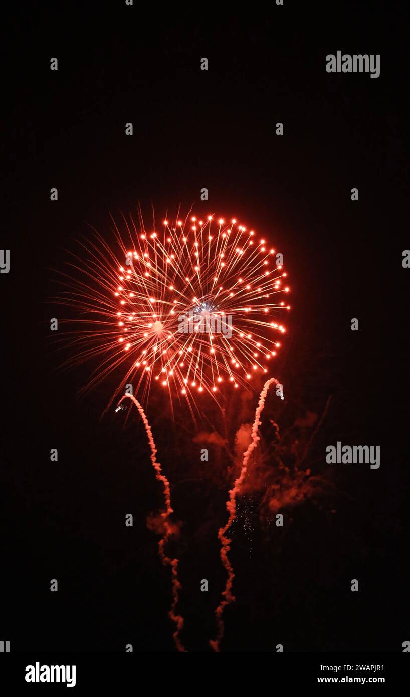 A radiant night sky illuminated by cascading exploding red fireworks ...