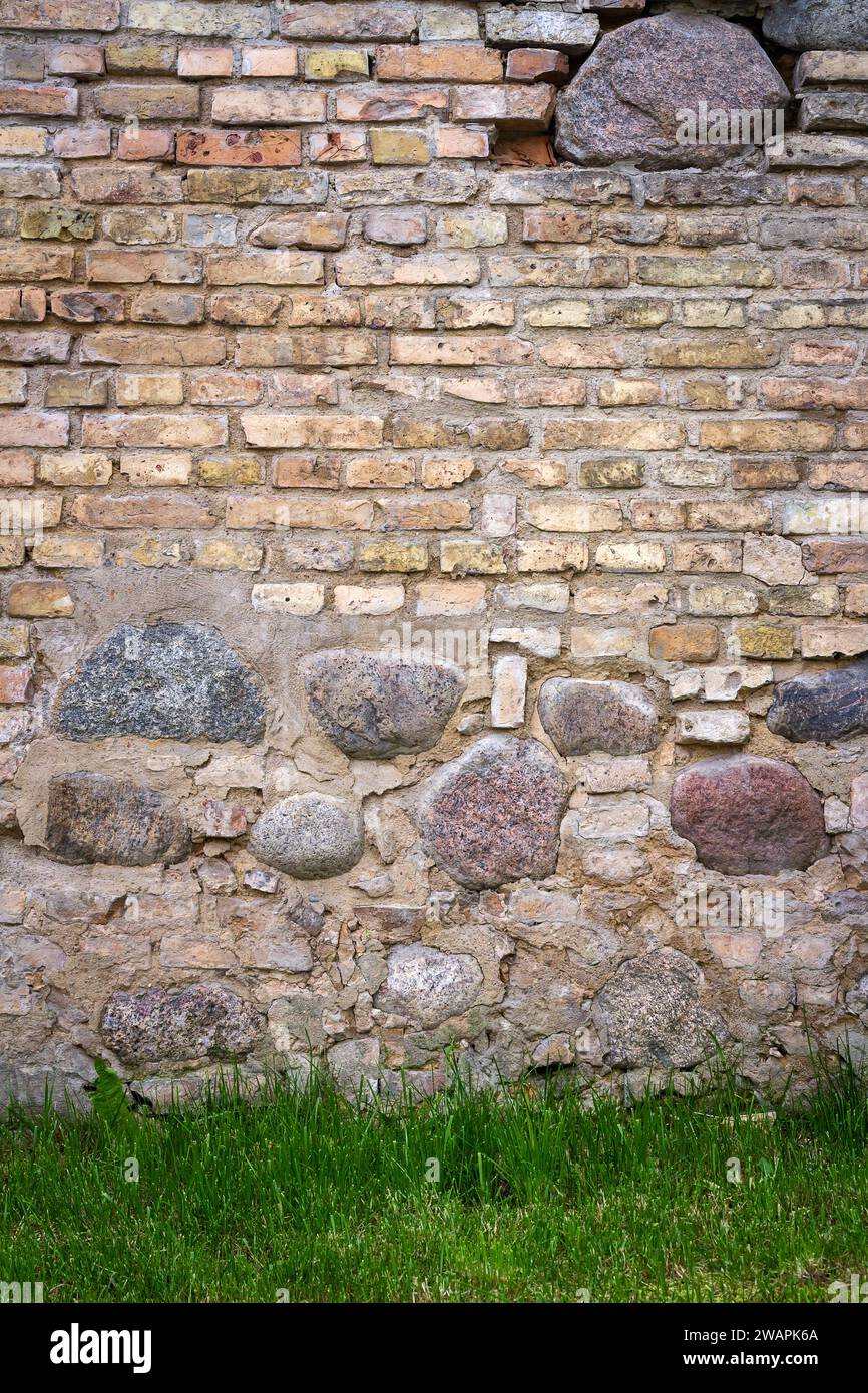 Wall texture with pieces of old bricks mixed with exposed round stones ...