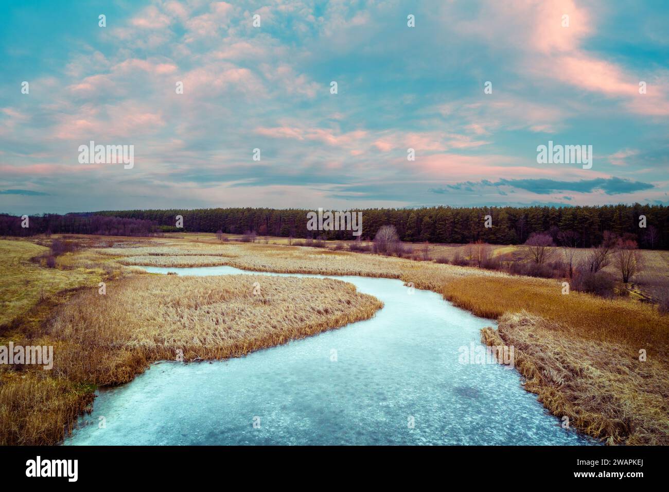 Aerial view of the countryside and frozen winding brook in the evening ...