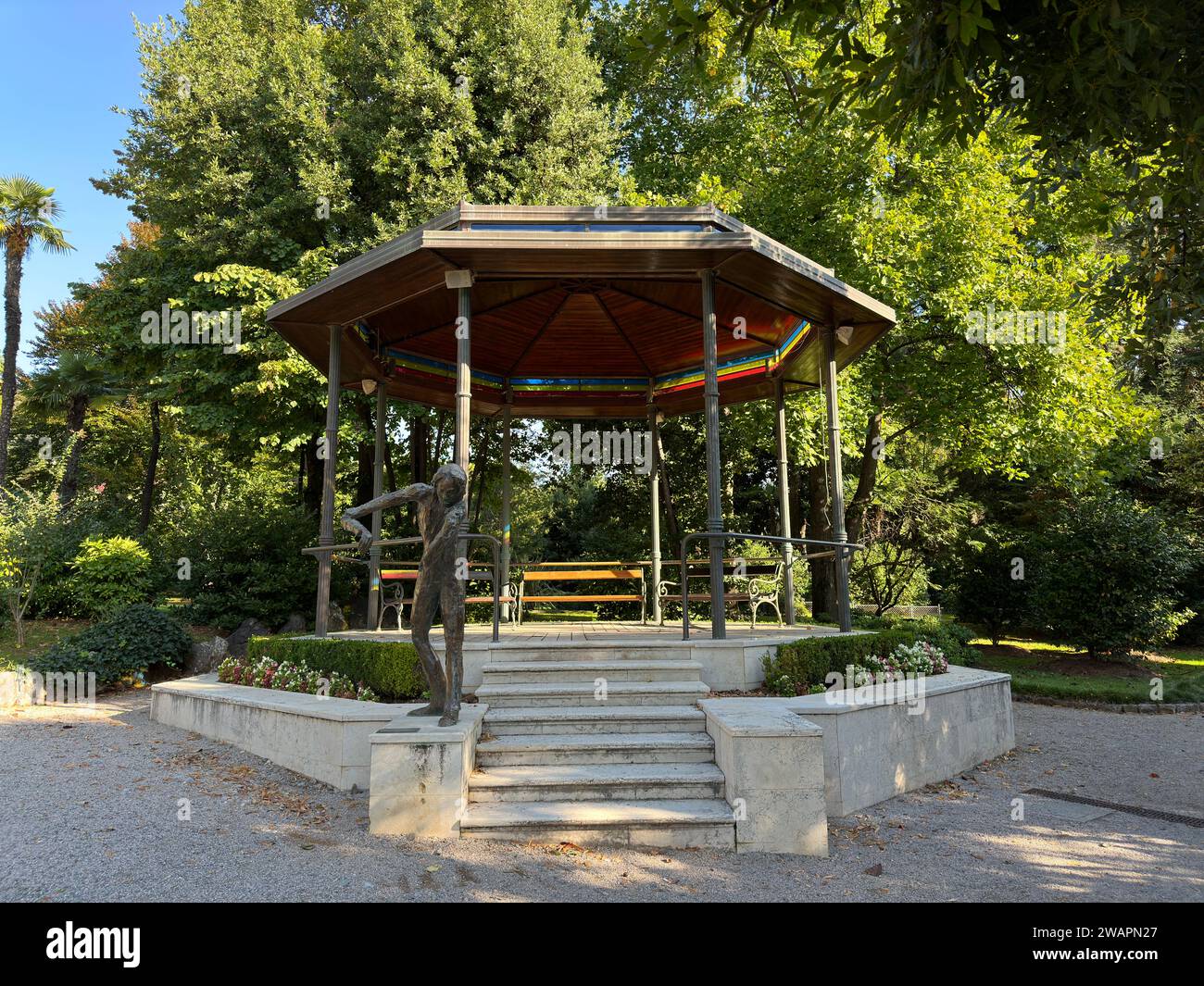 A picturesque outdoor gazebo with a wooden bench and steps, set in a ...