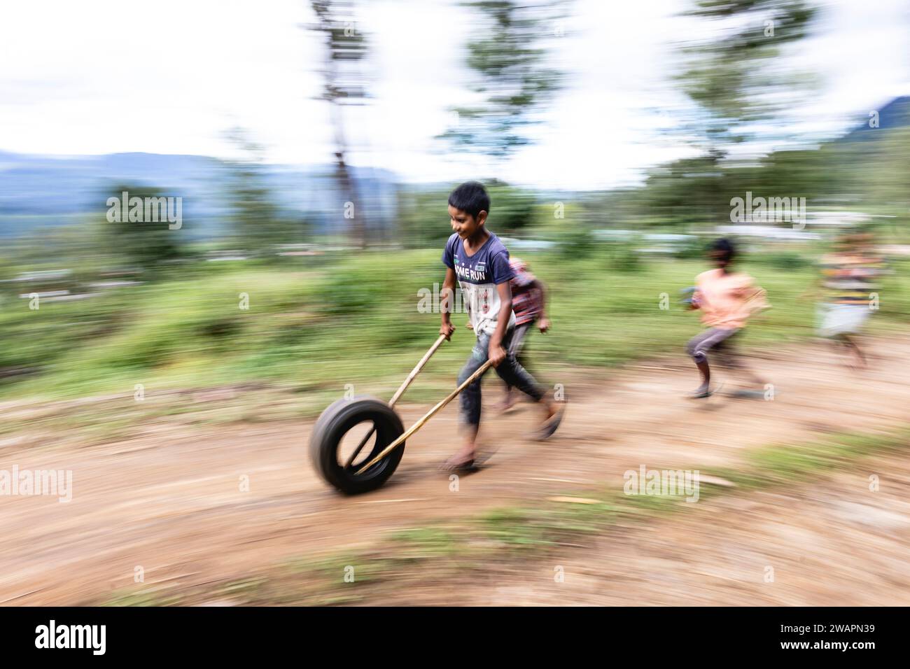 boy plays hoop and stick with a tyre in a hillside in Sri Lanka ...