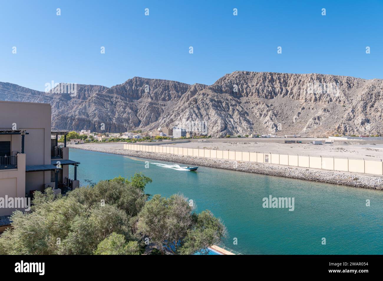A Boat on the West Sea Canal with Khasab town and cliffs beyond ...