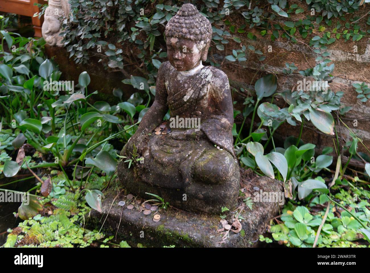 This vibrant garden features a detailed stone statue surrounded by lush ...