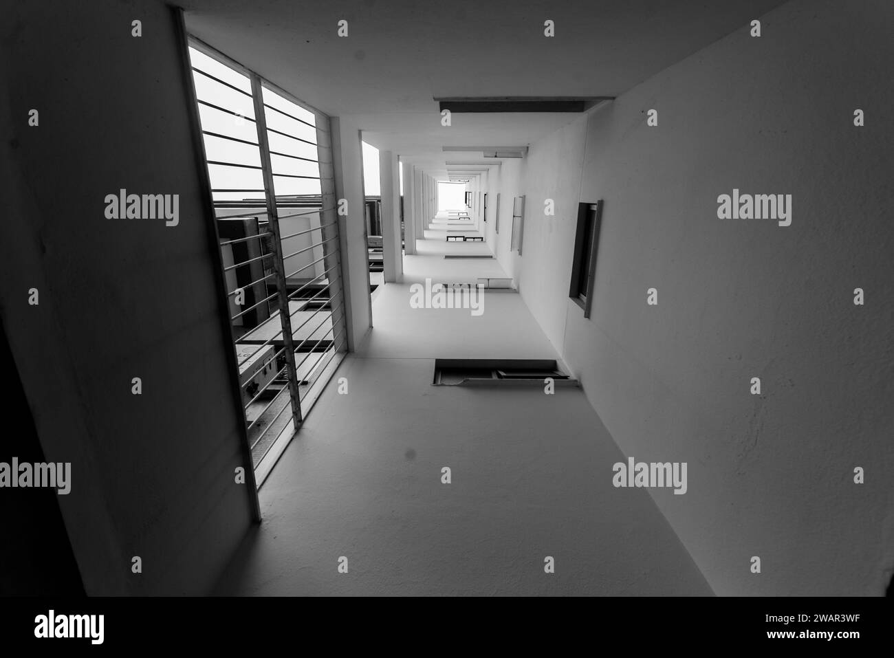 This image depicts a hallway in an apartment with two windows ...