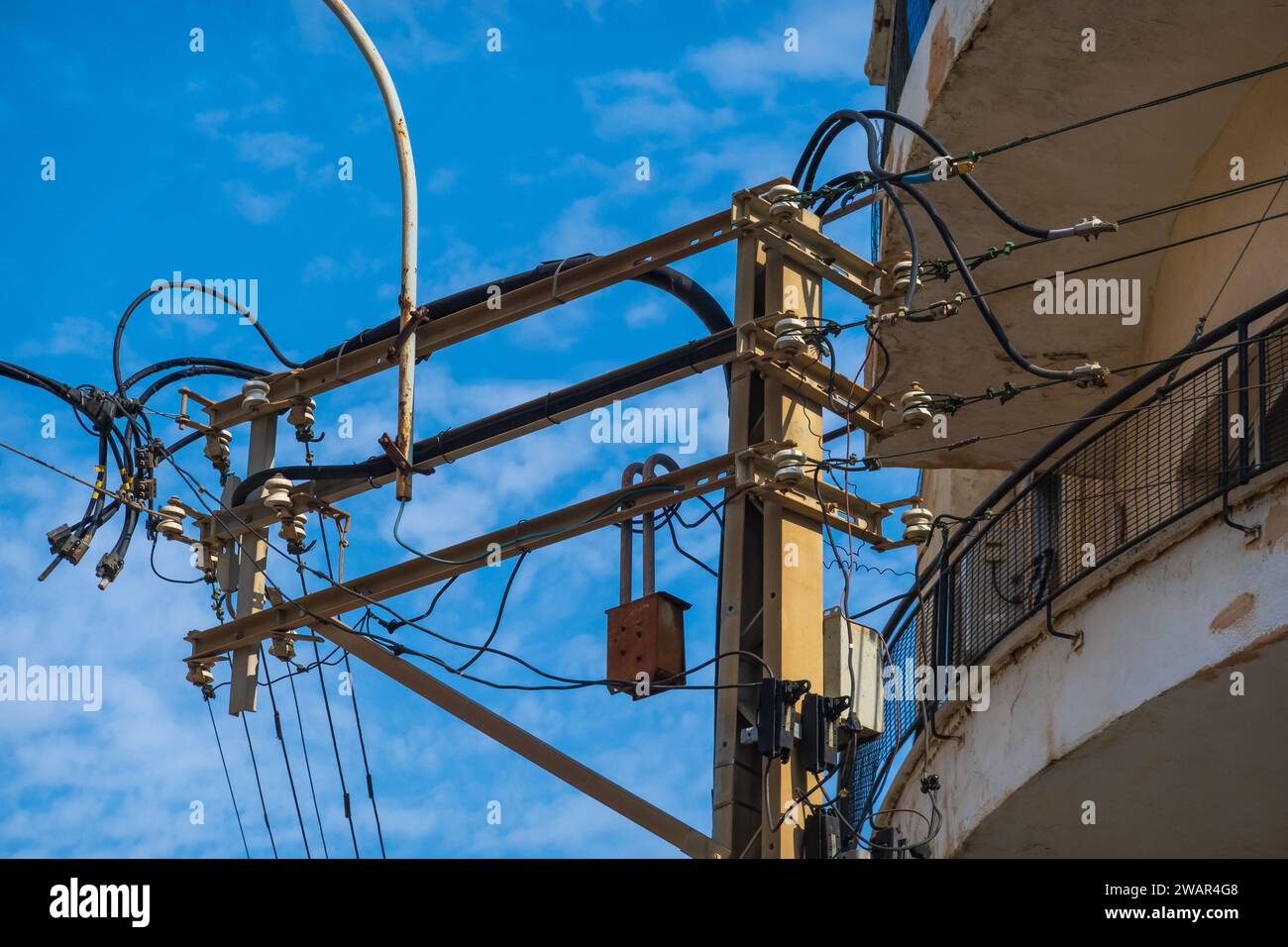 Complex web of power lines and transformers against a clear blue sky ...