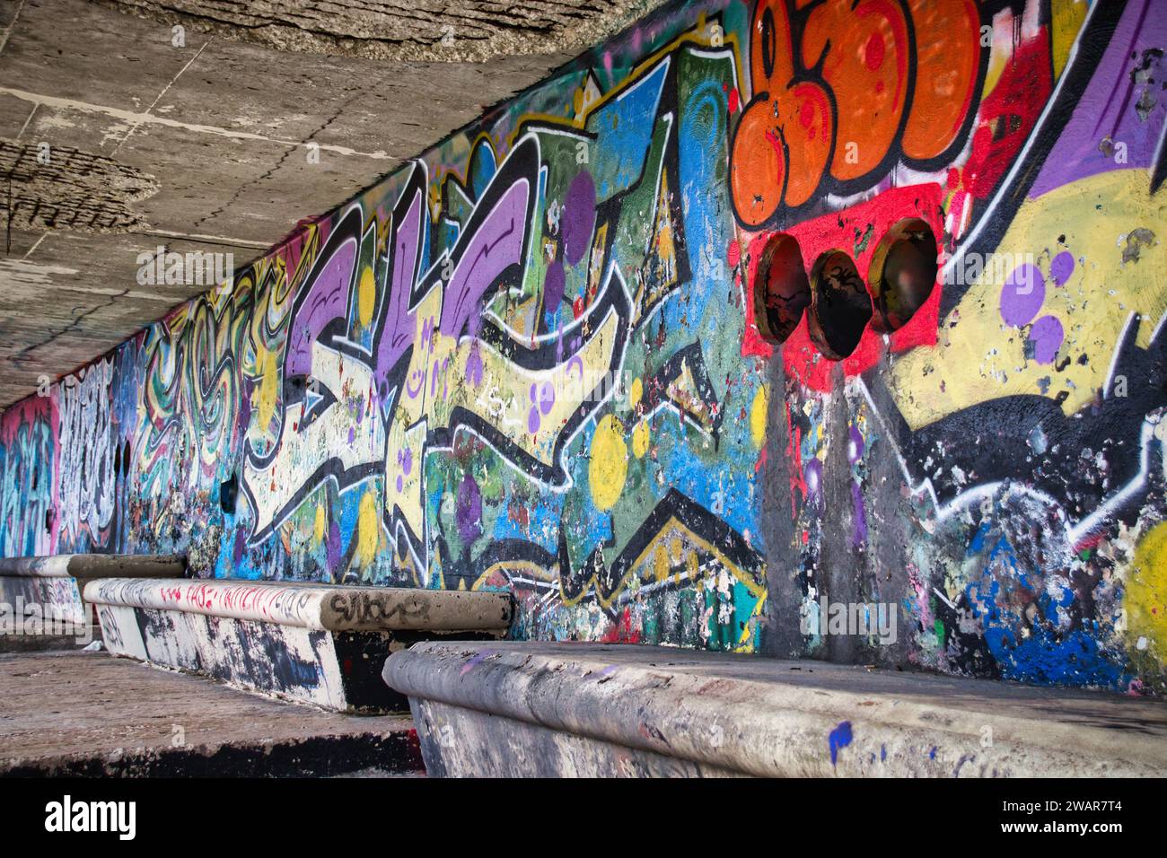 Colorful graffiti spray-painted on an urban wall in an underpass tunnel ...