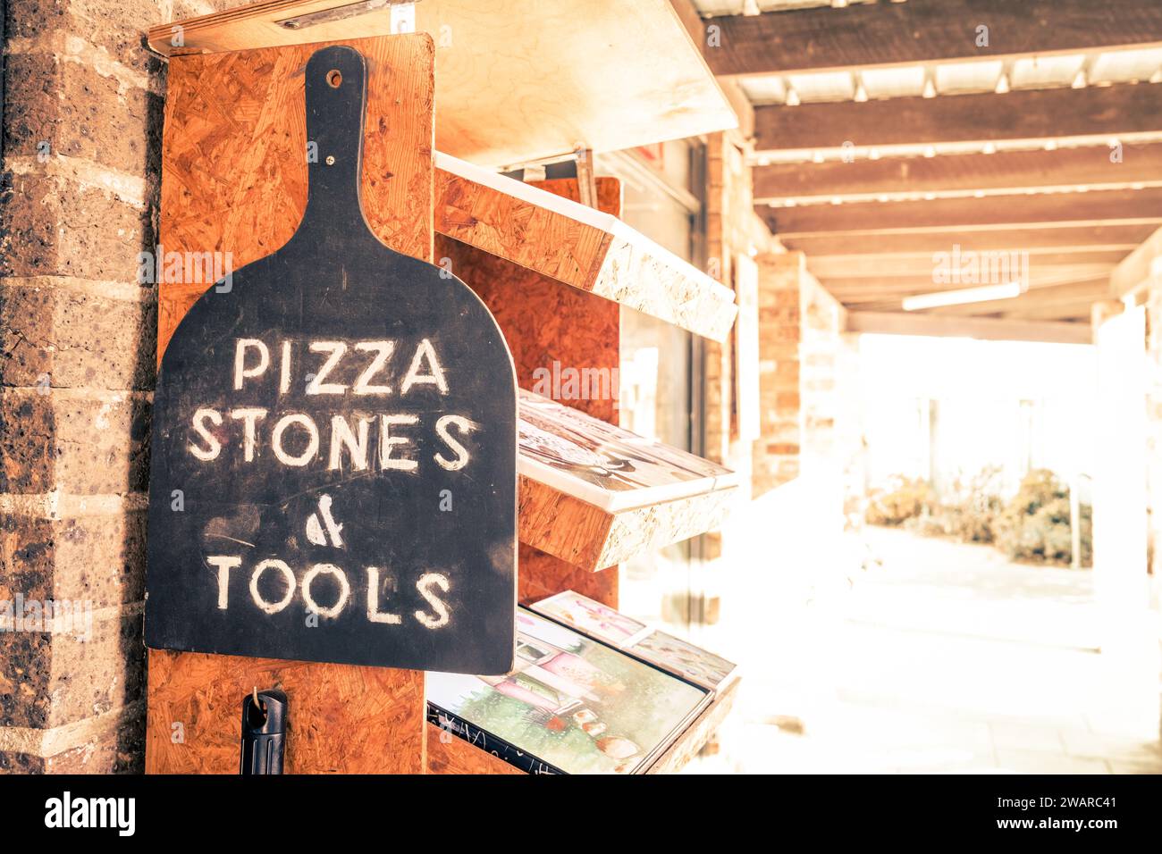A close up image of a pizza paddle leaning against a brick wall with a ...