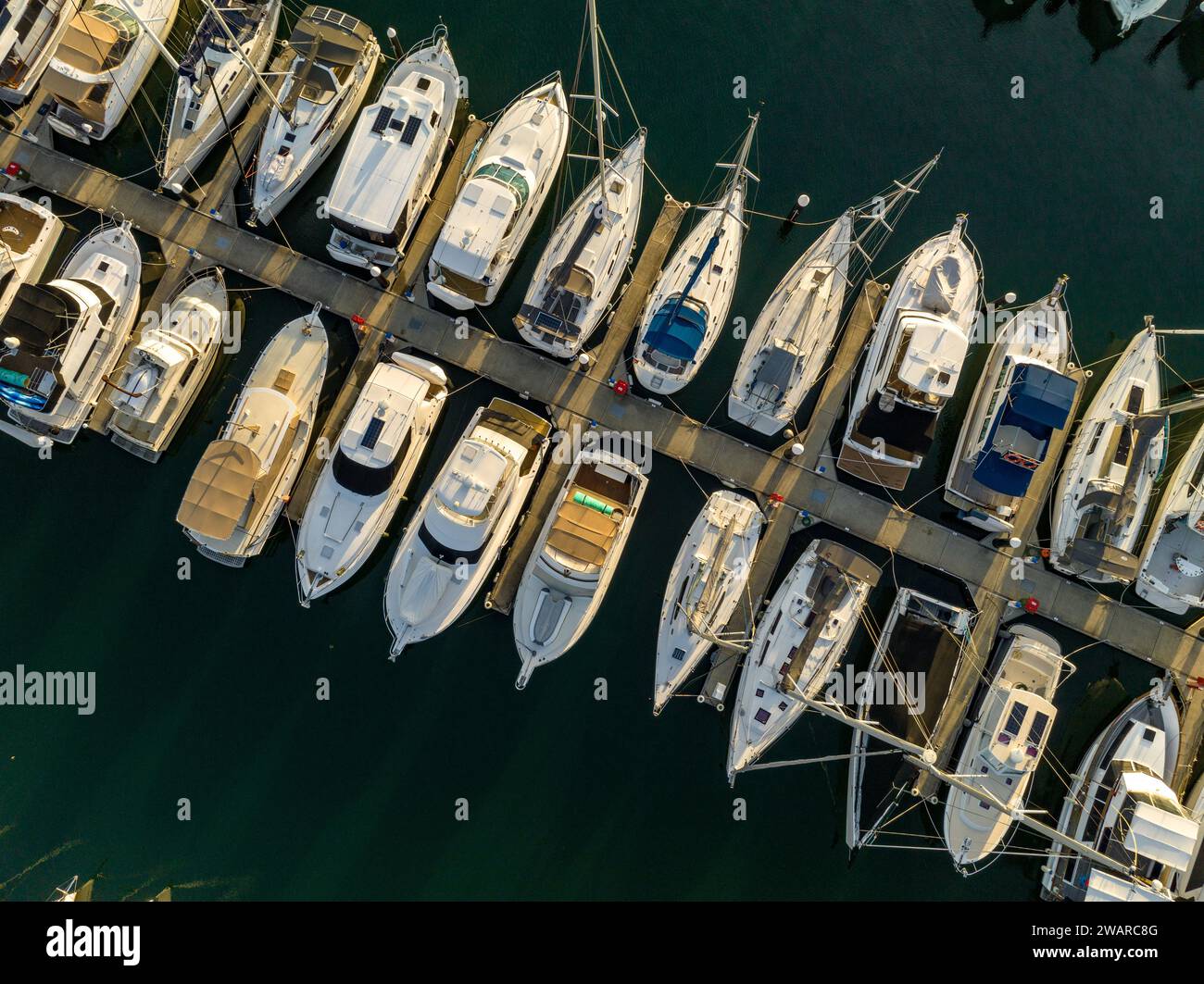 A tranquil scene of several sailing boats docked alongside a pier in a ...