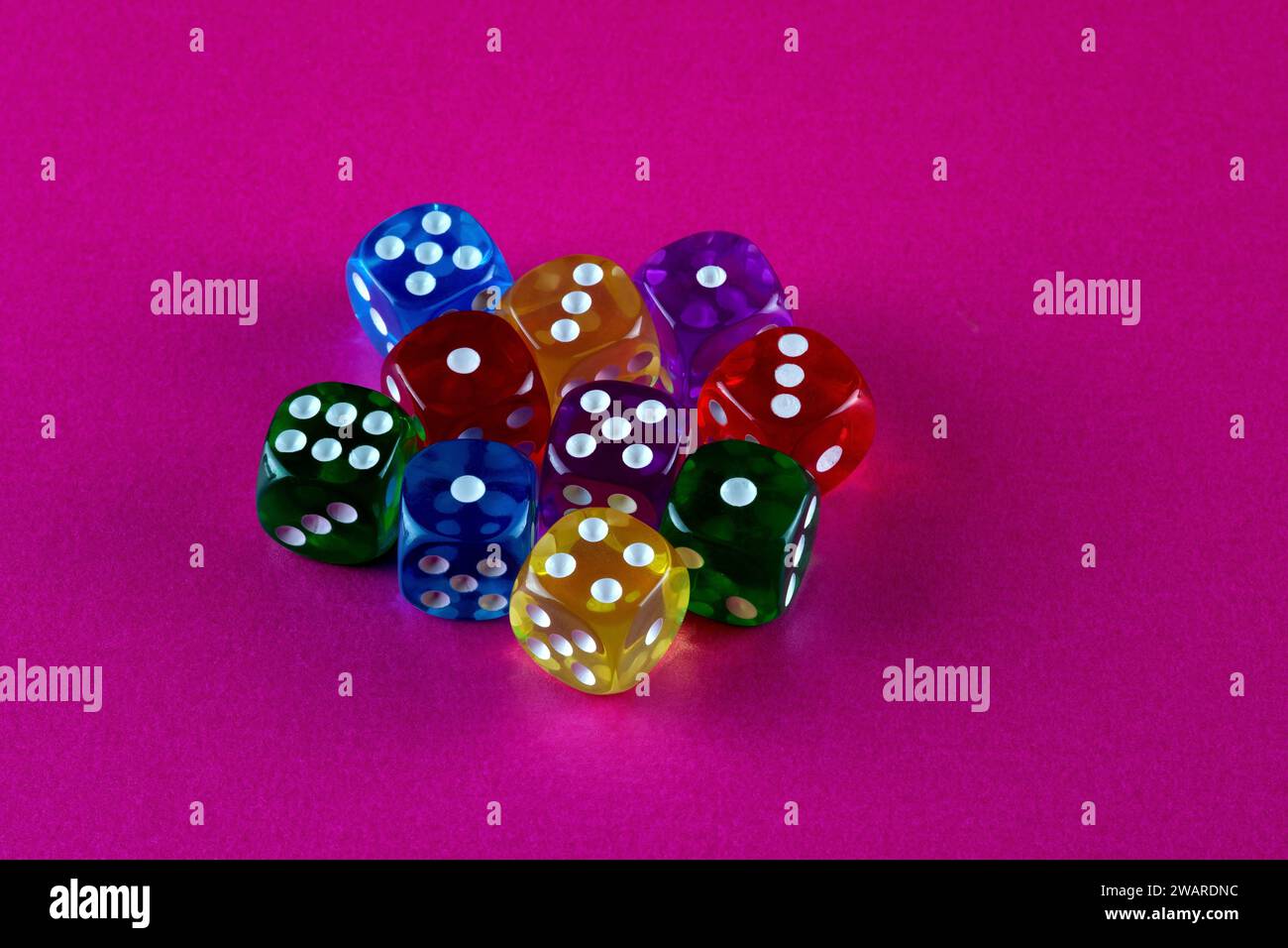 Coloured plastic gaming dice on a pink table top Stock Photo - Alamy