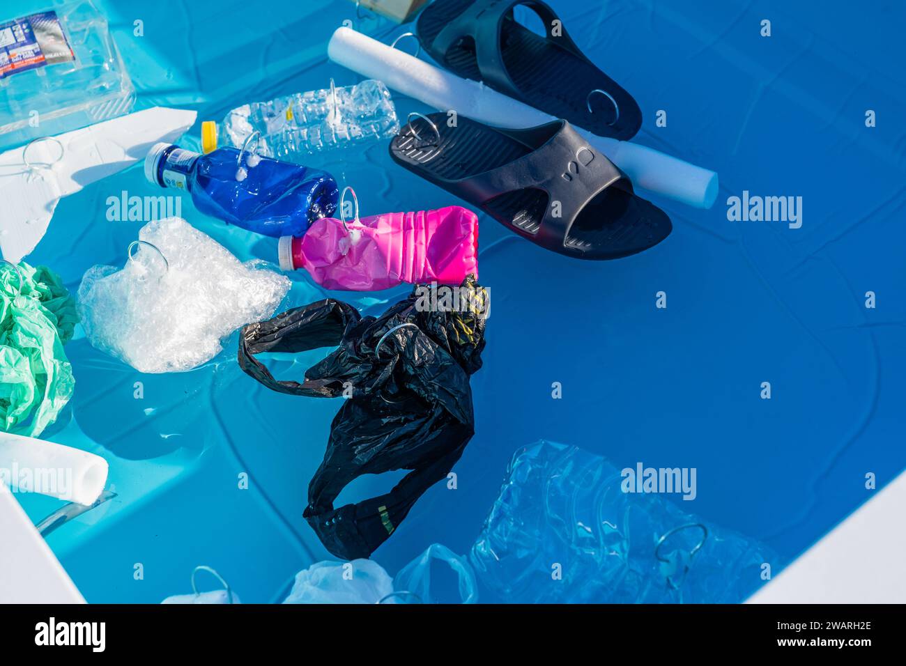 An assortment of Plastic garbage floating in a pool to raise awareness ...