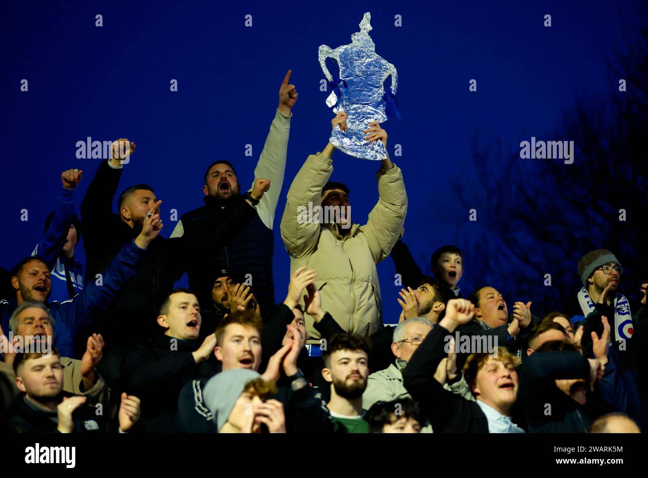 A fan in the stands holds up a replica of the FA Cup trophy at the end ...