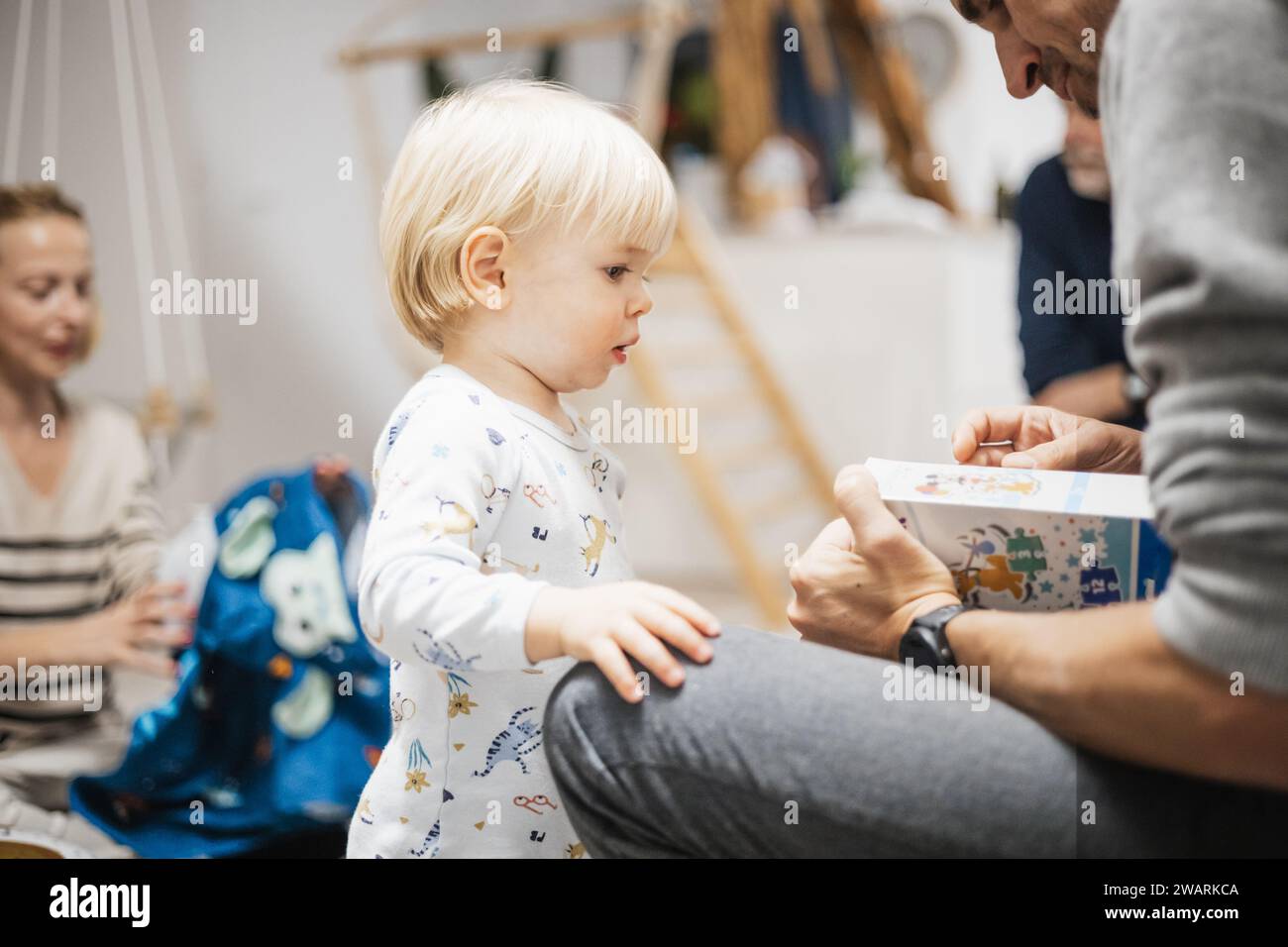 Cute little blond Caucasian toddler unpacking Christmas or Birthday ...