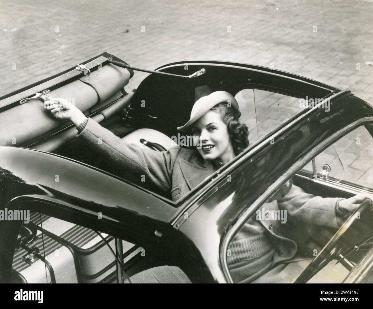 Young stylish woman opening the capote of a FIAT 500 Topolino car ...