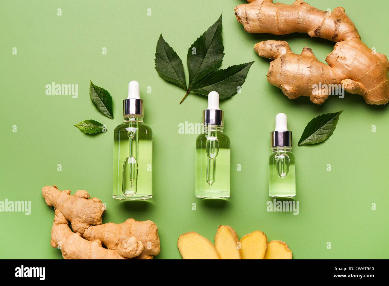 Bottles of ginger cosmetic oil and leaves on green background Stock ...