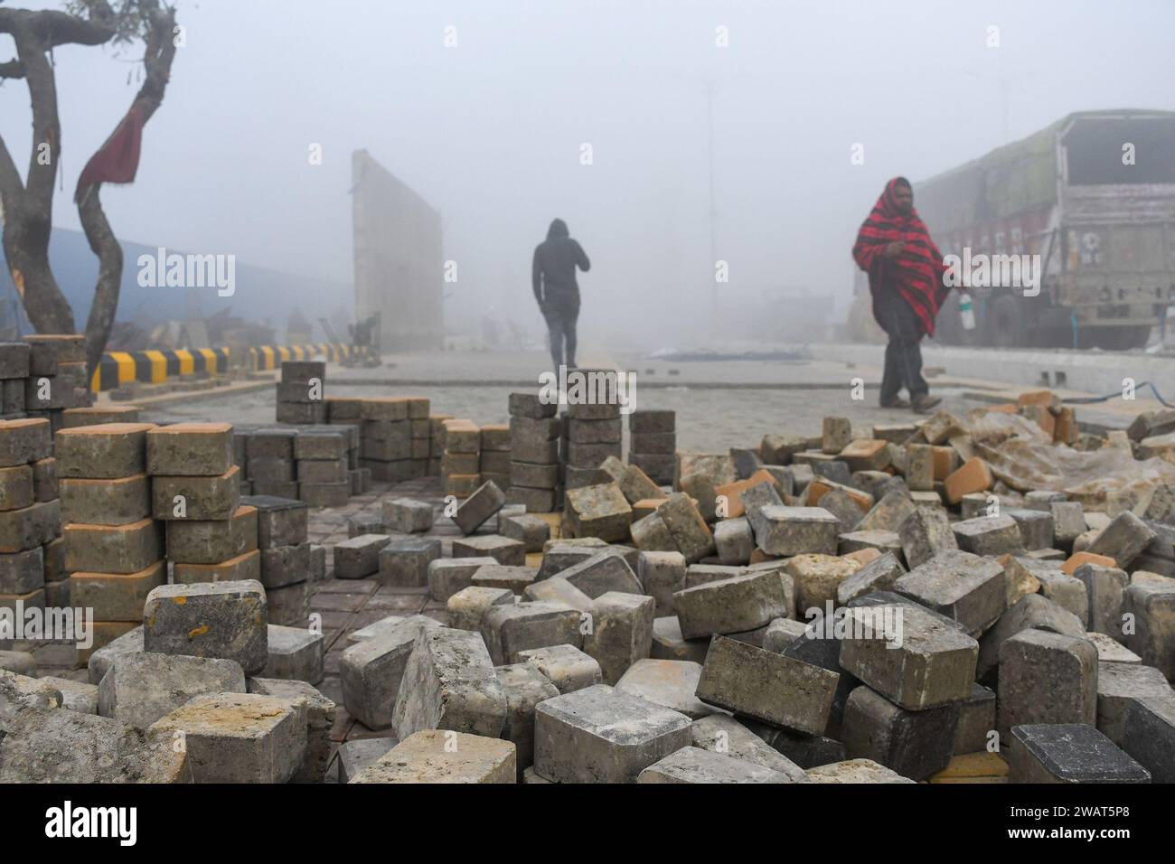 Labourers walk past paving stones laid over a newly constructed ...