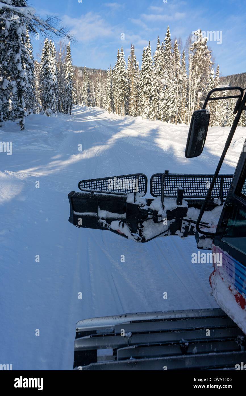 A ride in the cabin of an open red snowcat, a view of the caterpillar ...