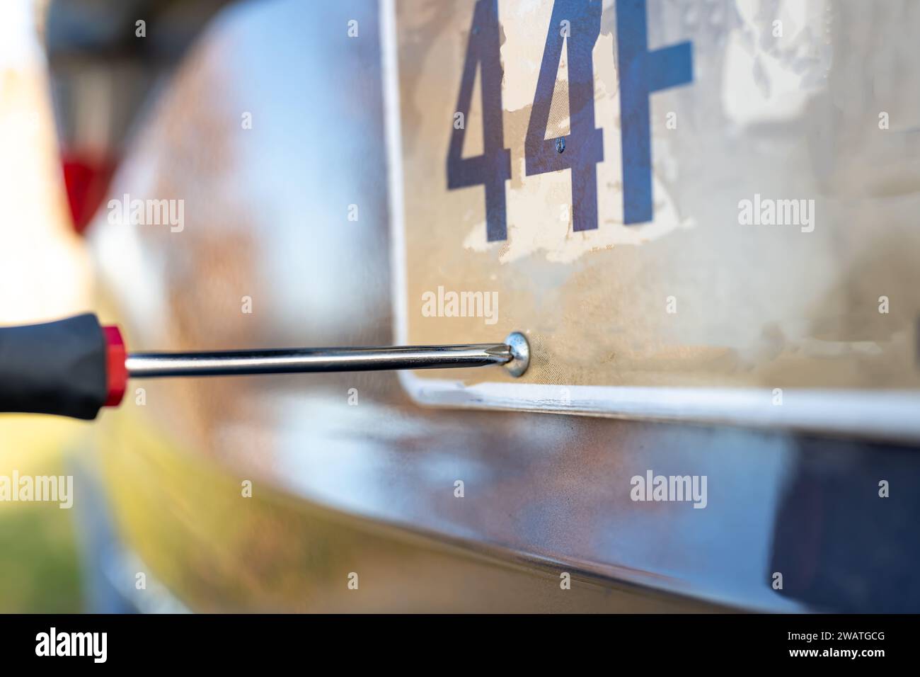 Using a screw driver to remove and replace a vehicle rear license plate ... Using a screw driver to remove and replace a vehicle rear license plate ...