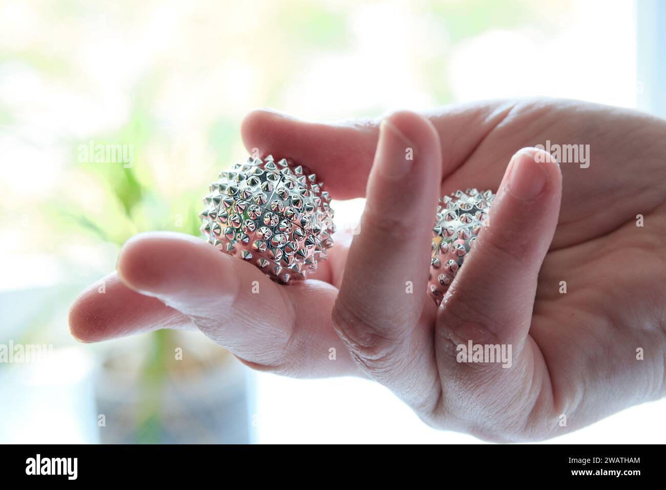 Silver metal magnetic balls in female hand. Spiky tool for hand massage ...