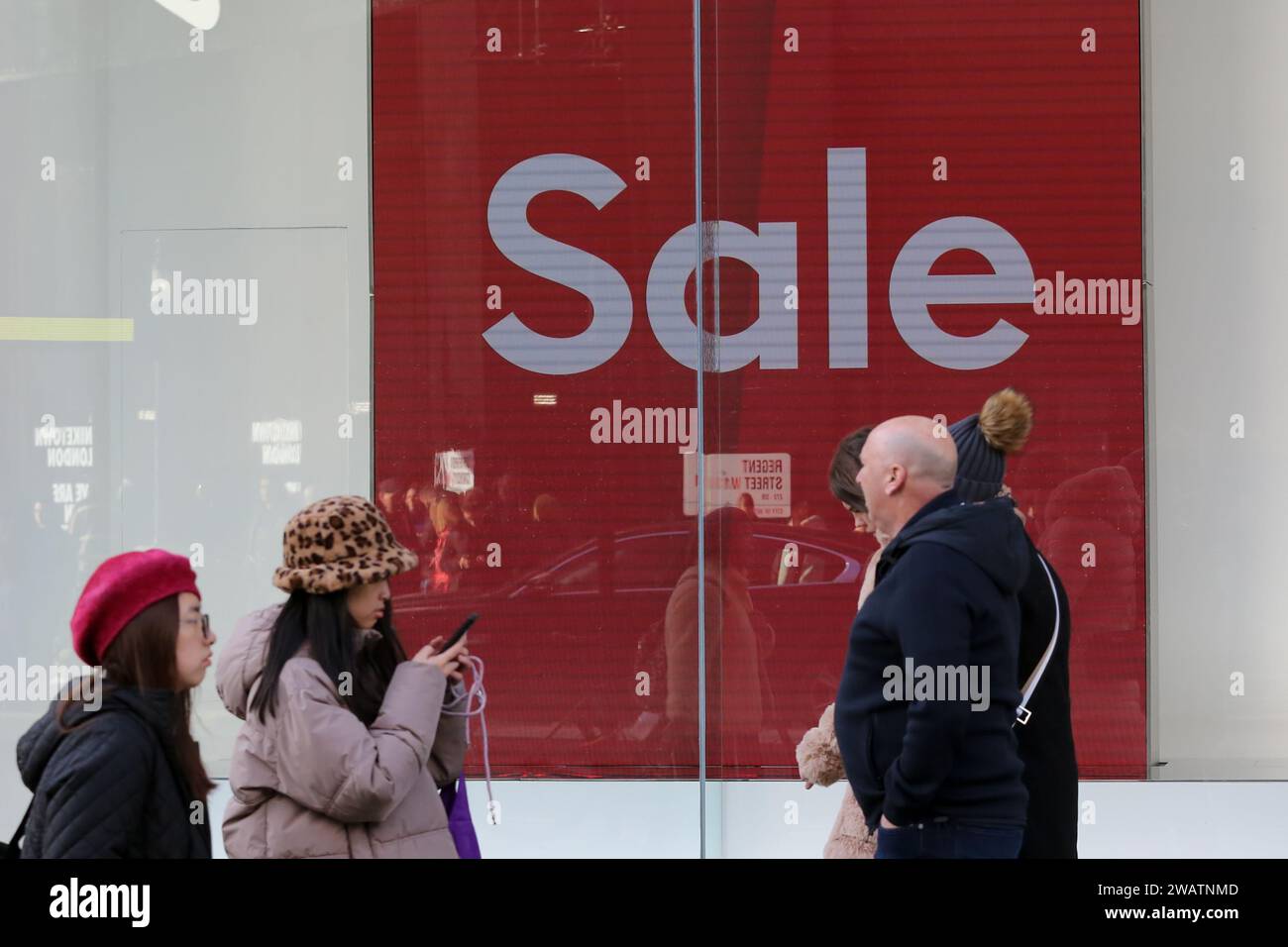 Shoppers walk past a sale sign in a store on Oxford Street in central ...