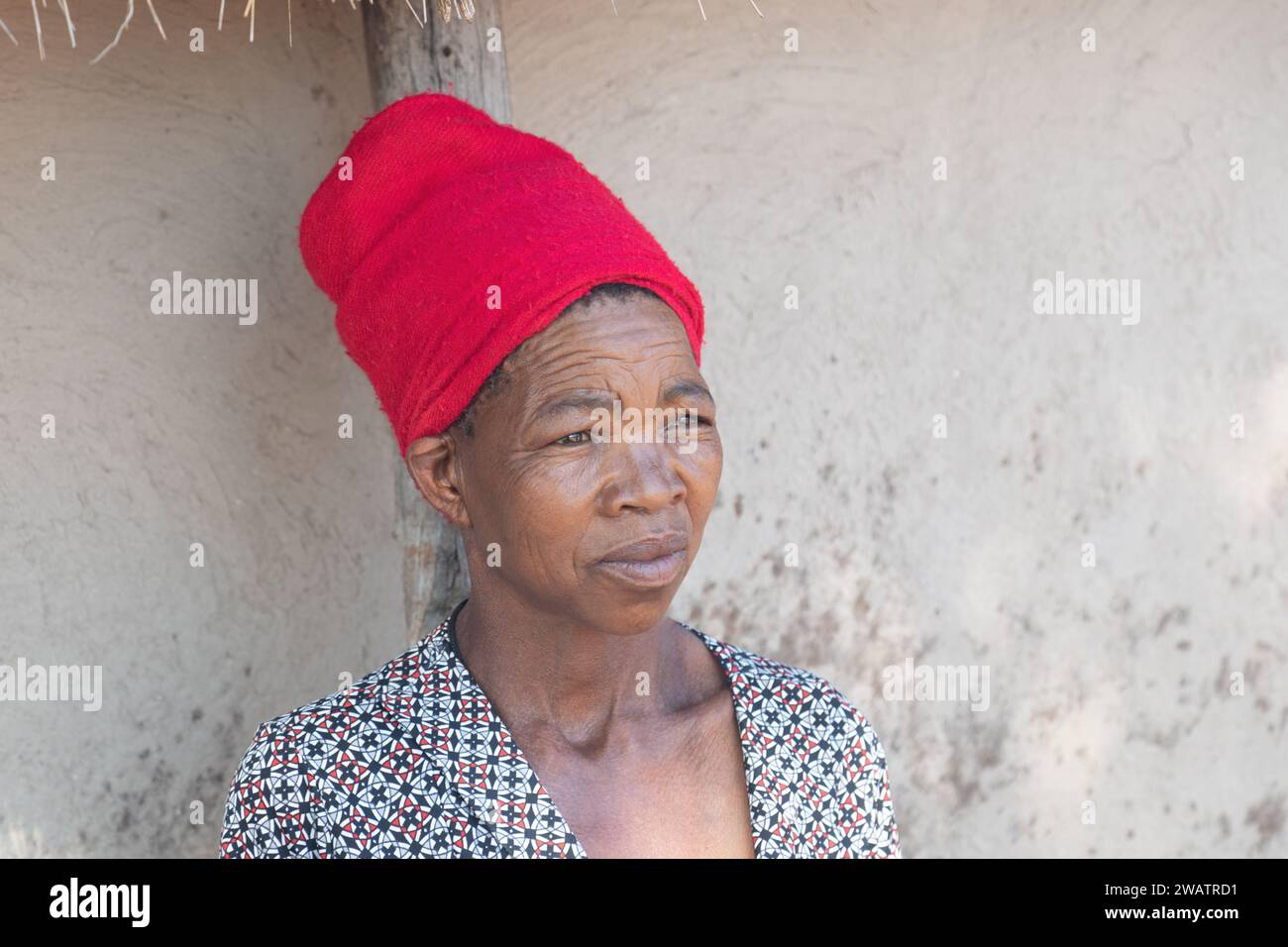old African woman with red scarf, natural light against the wall of the ...