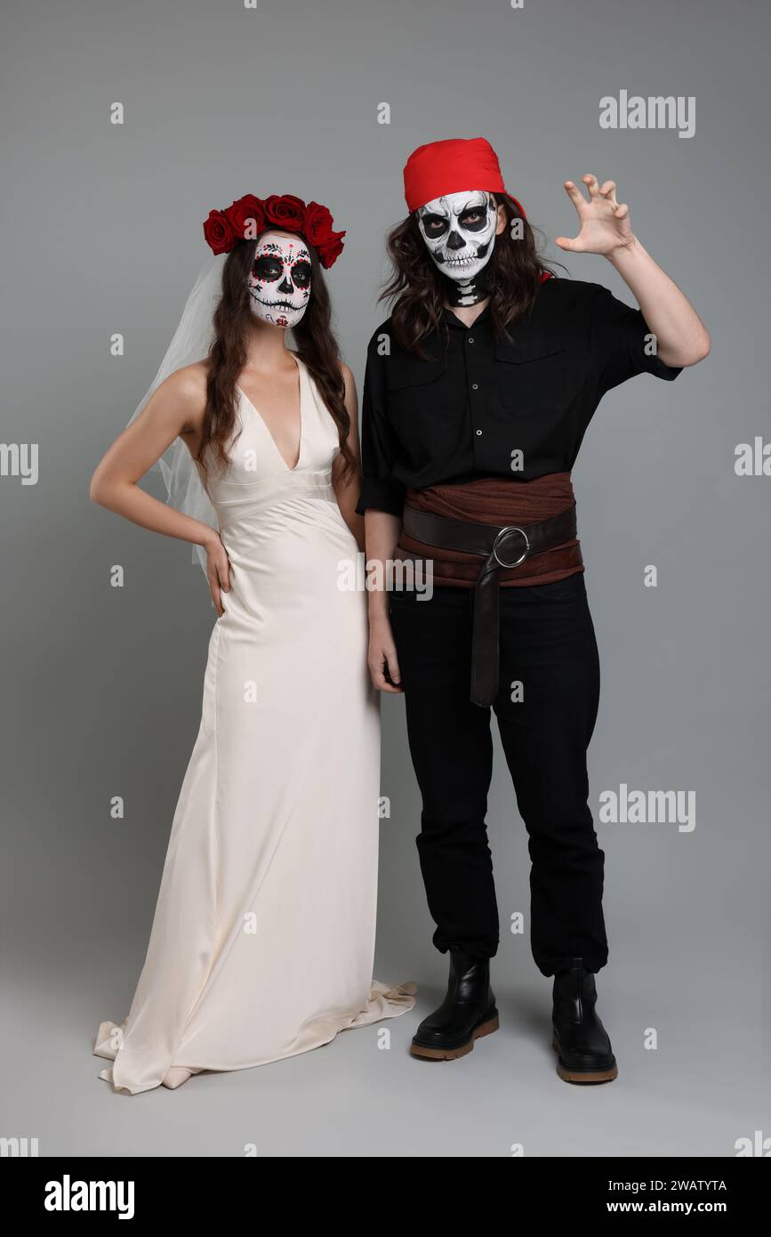 Couple in scary bride and pirate costumes on light grey background ...