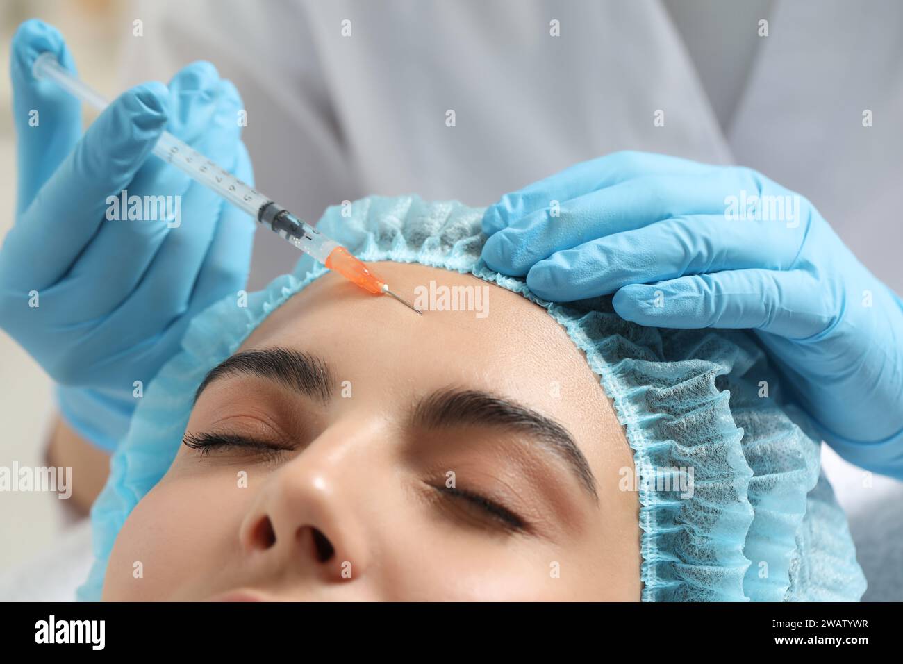 Doctor giving facial injection to young woman in clinic, closeup ...