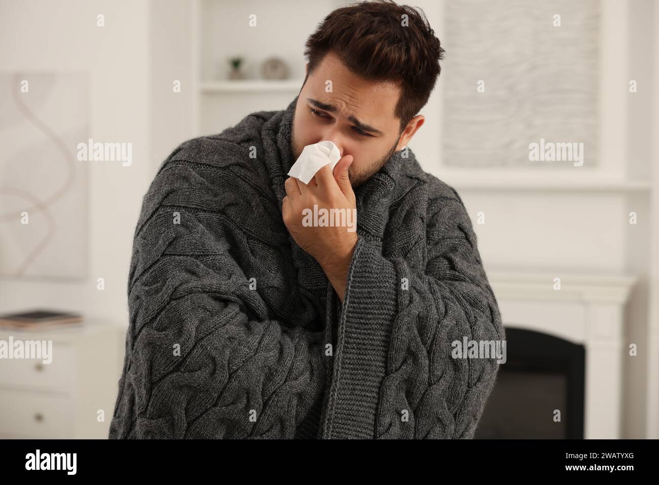 Sick man wrapped in blanket with tissue blowing nose at home. Cold ...
