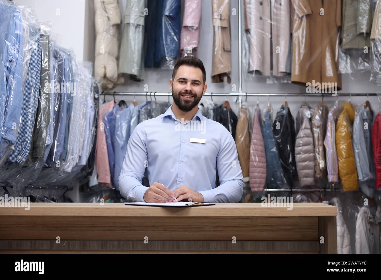 Dry-cleaning service. Happy worker at counter indoors Stock Photo - Alamy