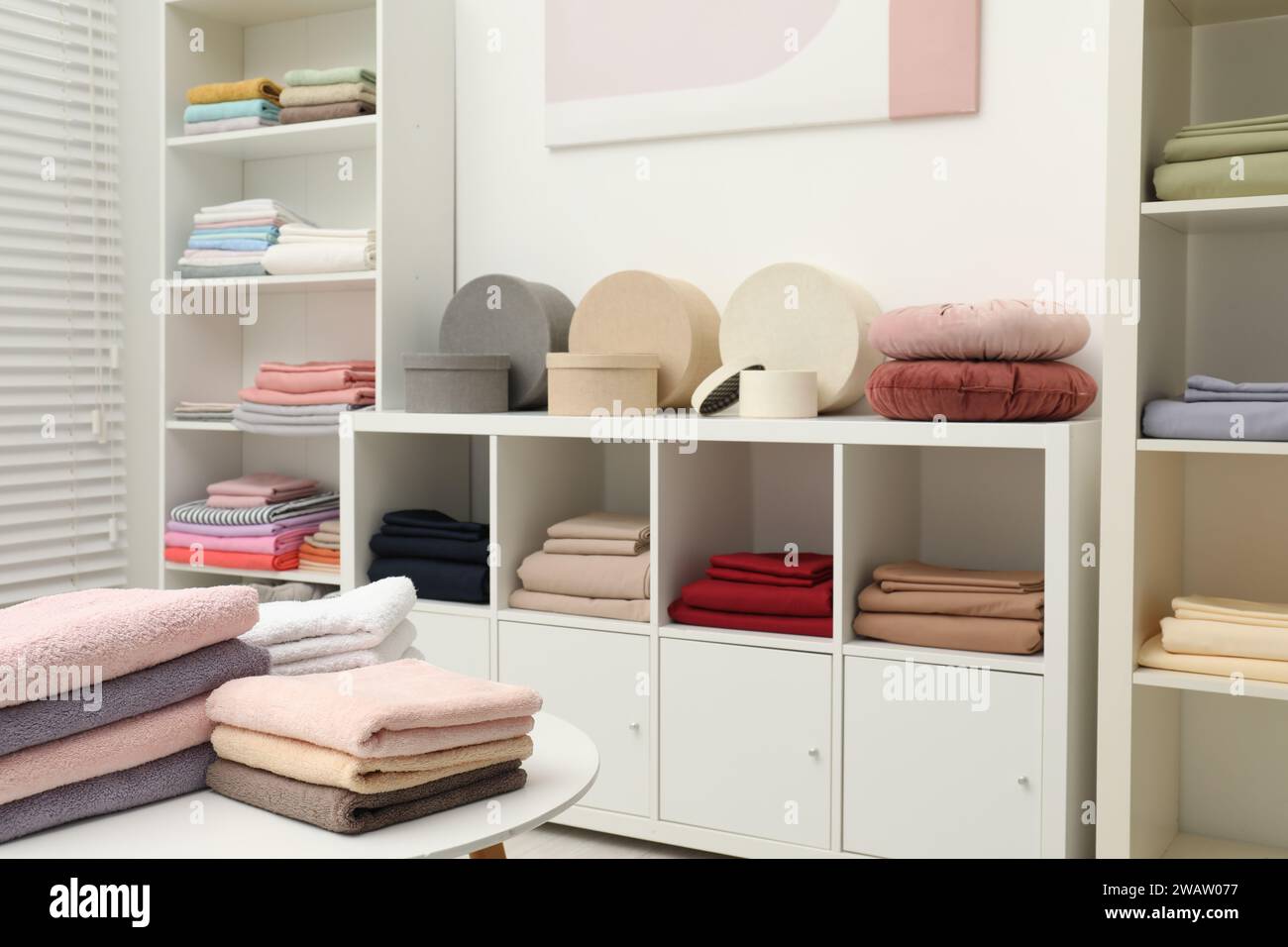 Different colorful bed linens and decorative boxes on display in home ...