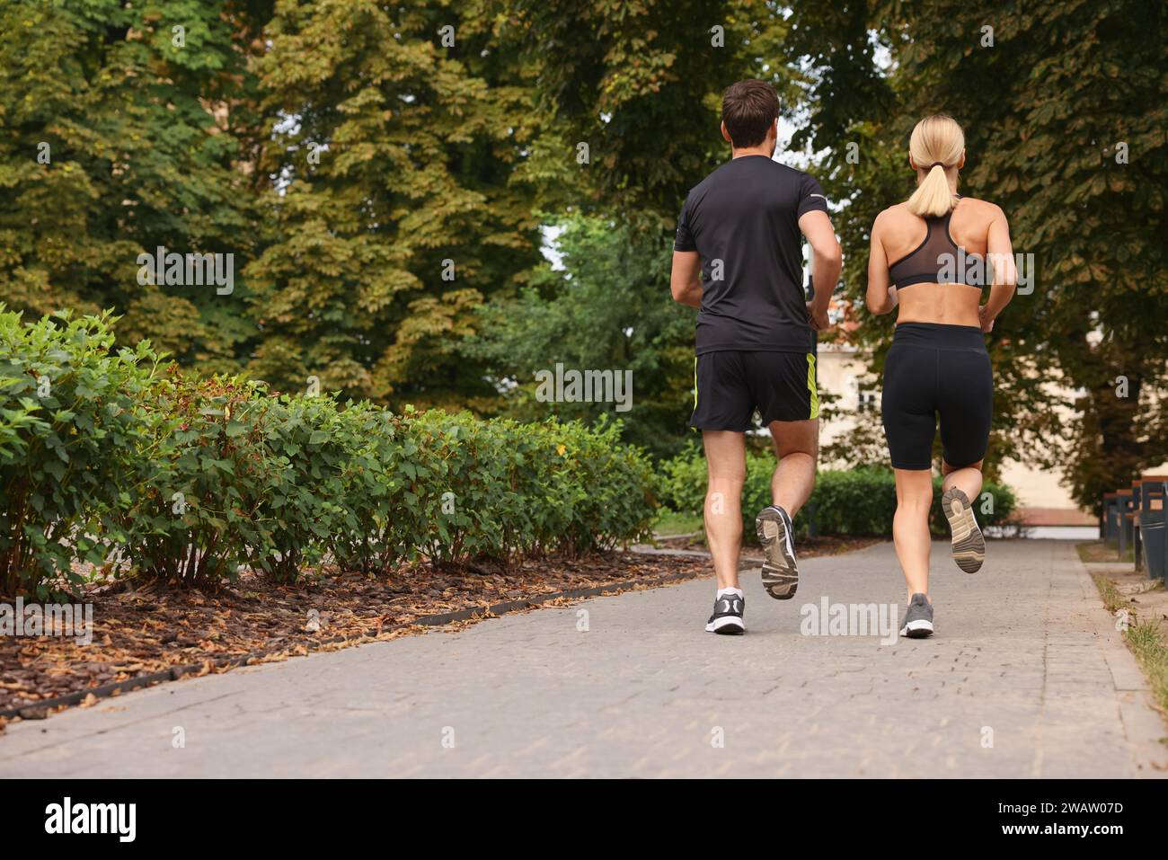 Healthy lifestyle. Couple running in park, back view with space for ...