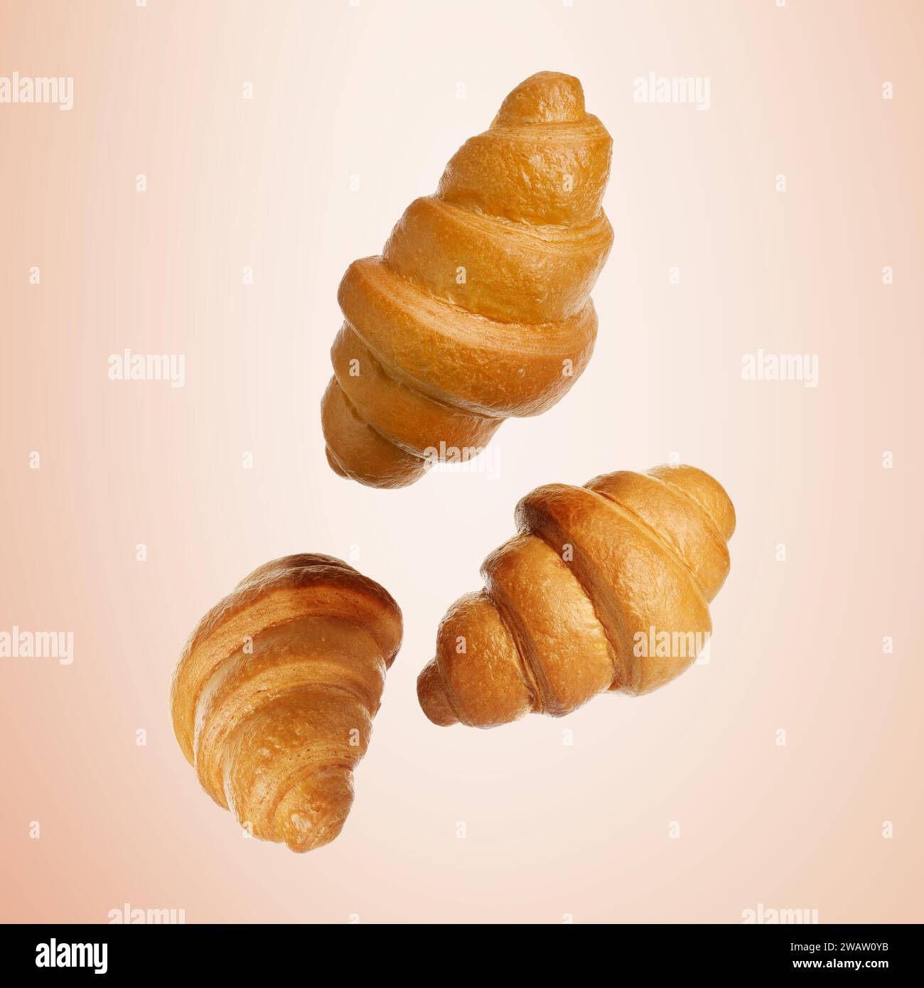 Golden croissants falling on beige gradient background Stock Photo - Alamy