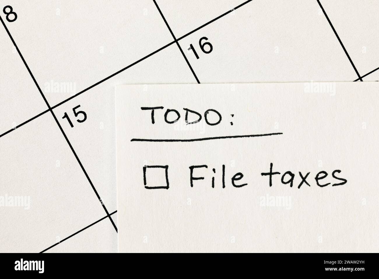 Hand written to-do list with 'File taxes' reminder written on a sticky ...