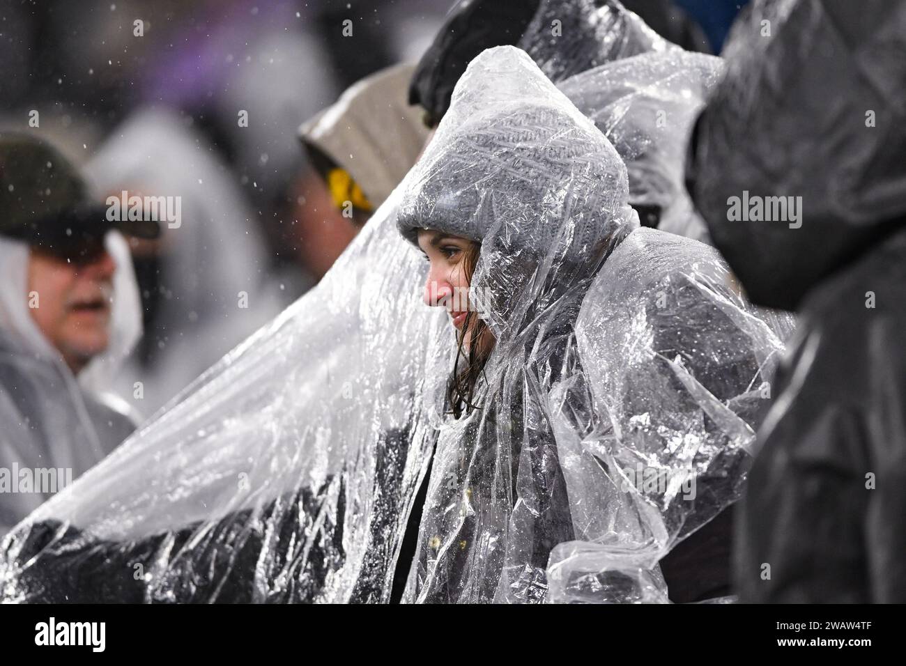 Fans attempt to stray dry during a cold rain as the Baltimore Ravens ...