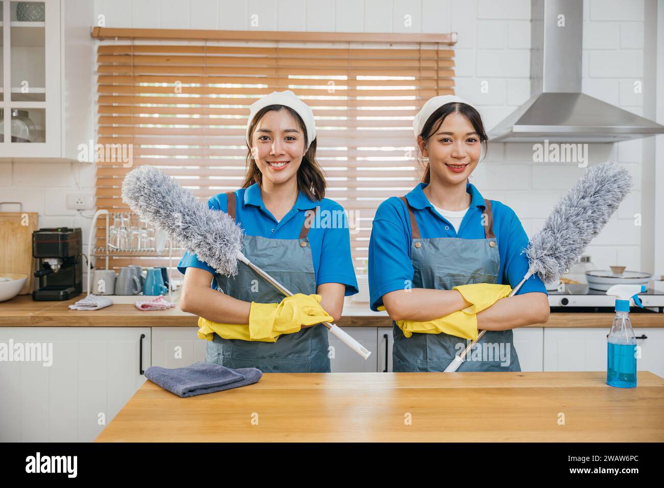 Two Asian young cleaning service women on kitchen counter with duster ...
