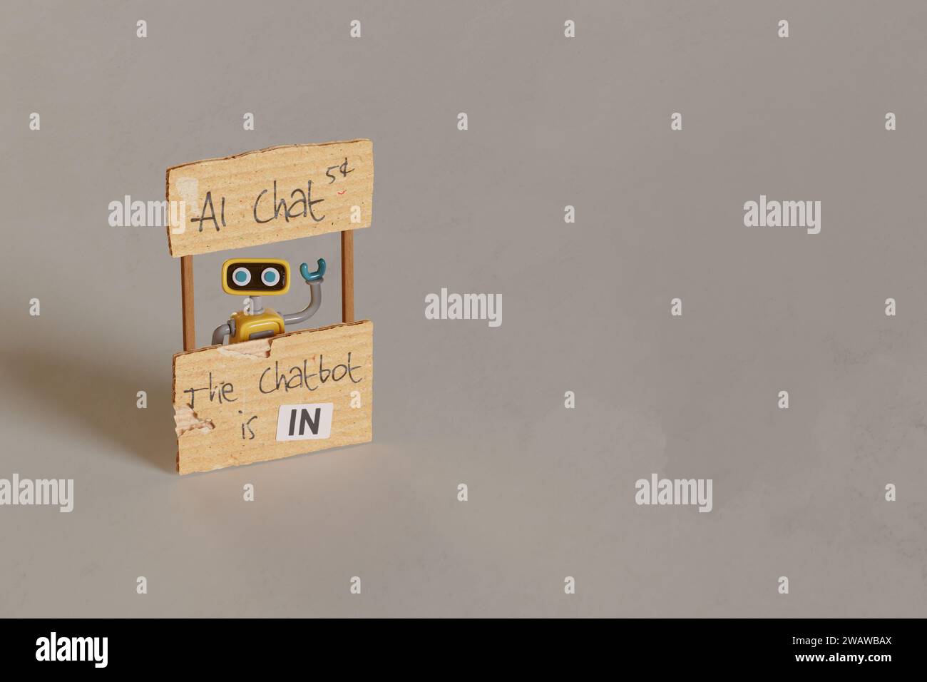 Plastic yellow toy robot manning an AI chat stand made of cardboard ...