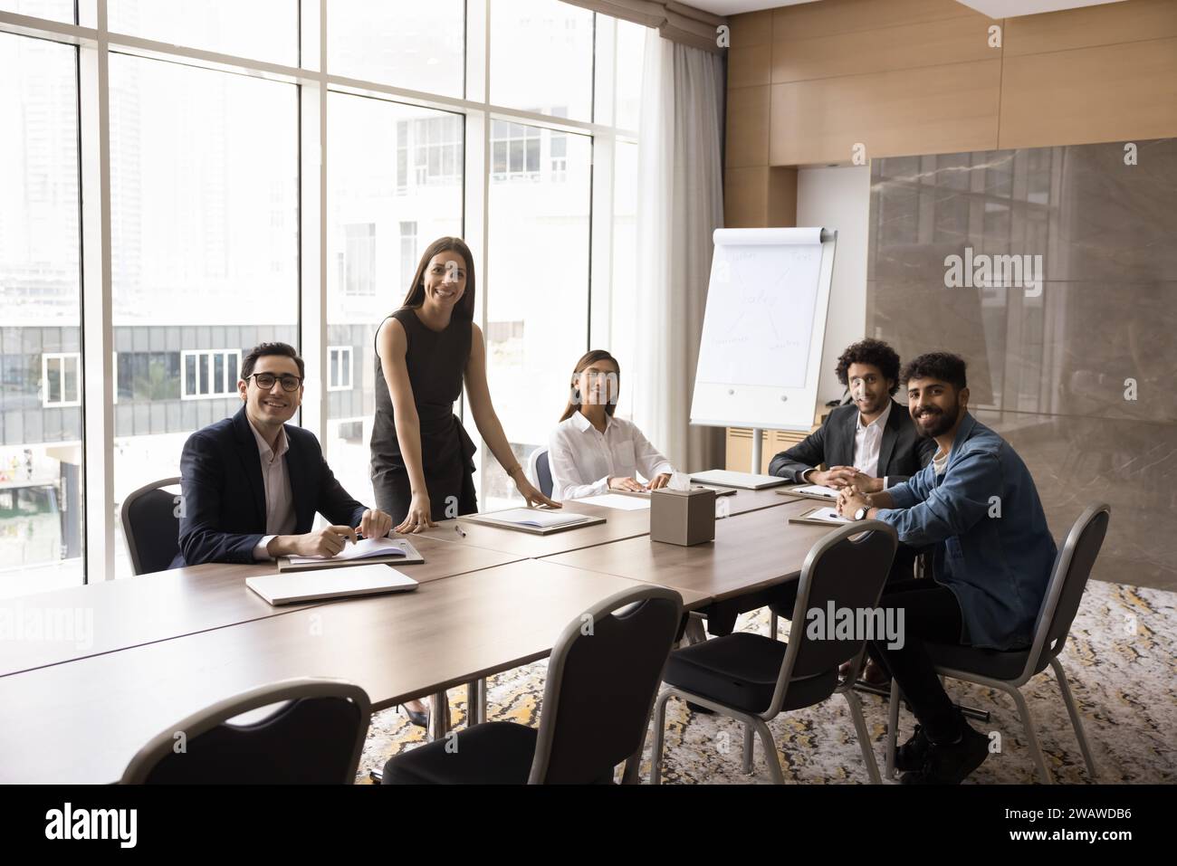 Happy business colleagues and young team leader meeting in boardroom ...