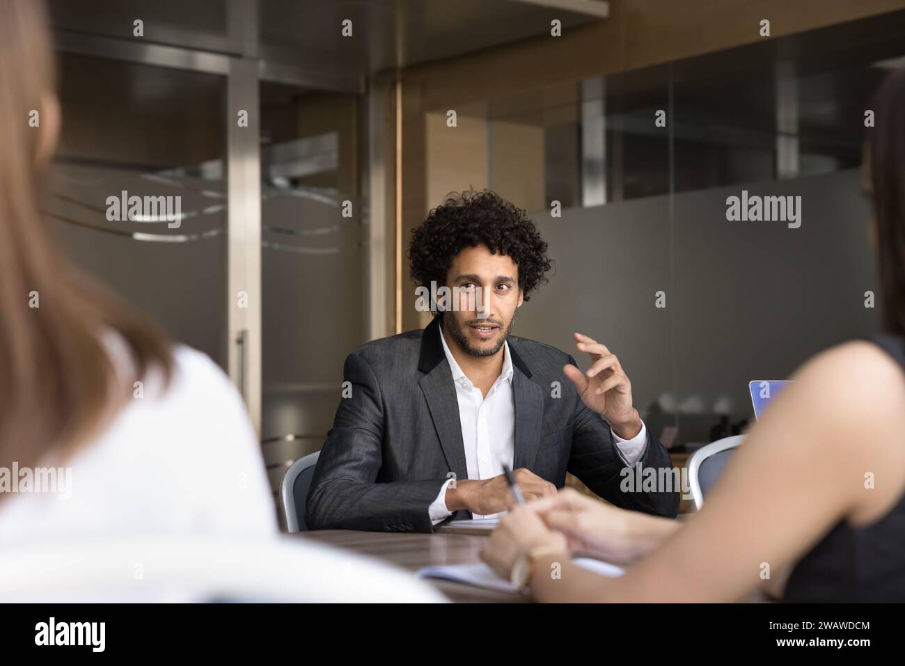Positive young Arab business professional man talking to HR managers ...