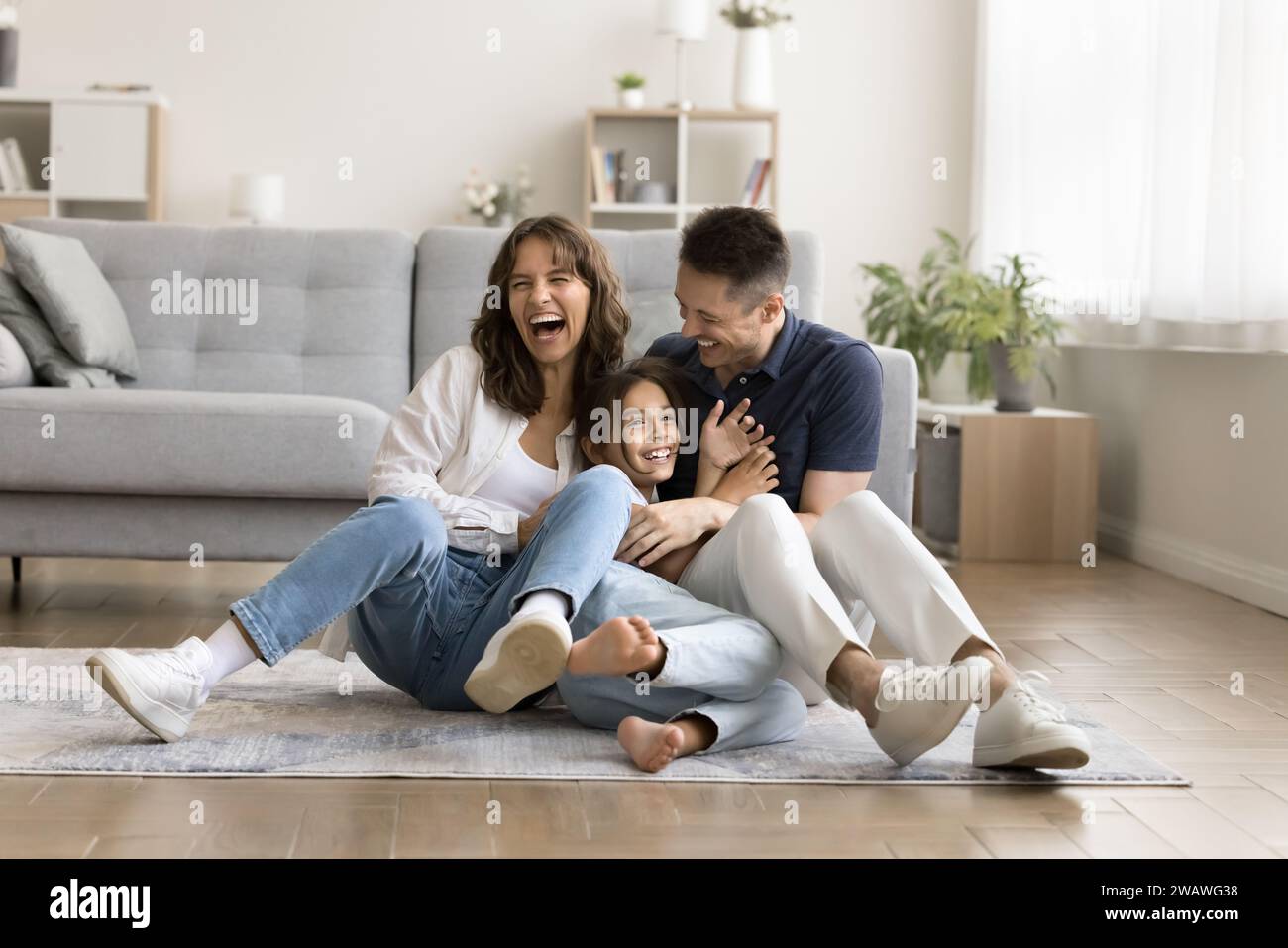 Cheerful excited parents tickling beloved kid girl, playing with child ...