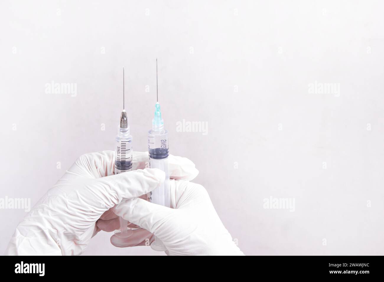 a doctor's hand holding a syringe of two sizes and filled with vaccine ...