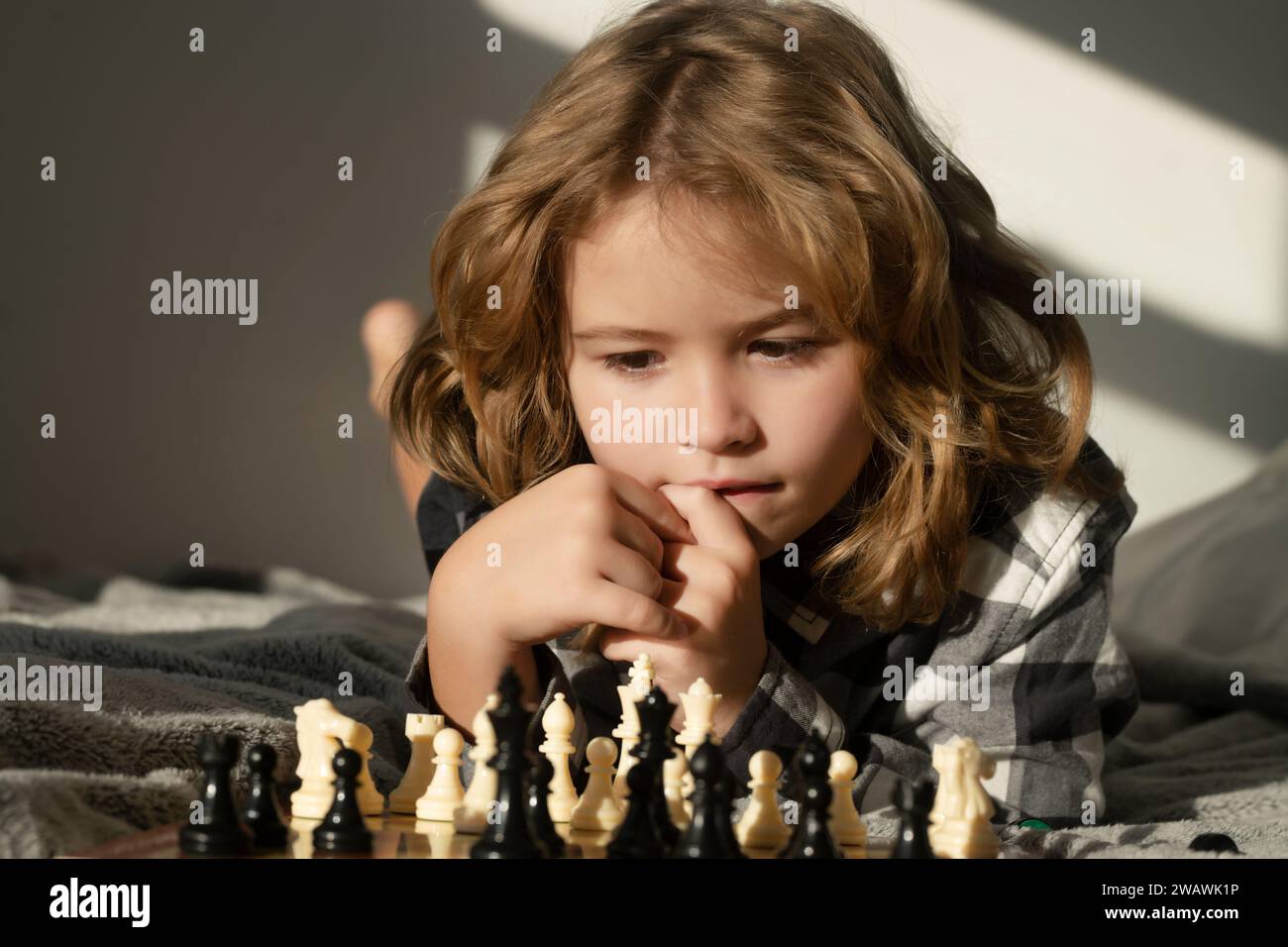 Little boy are playing chess at home. Clever concentrated and thinking ...