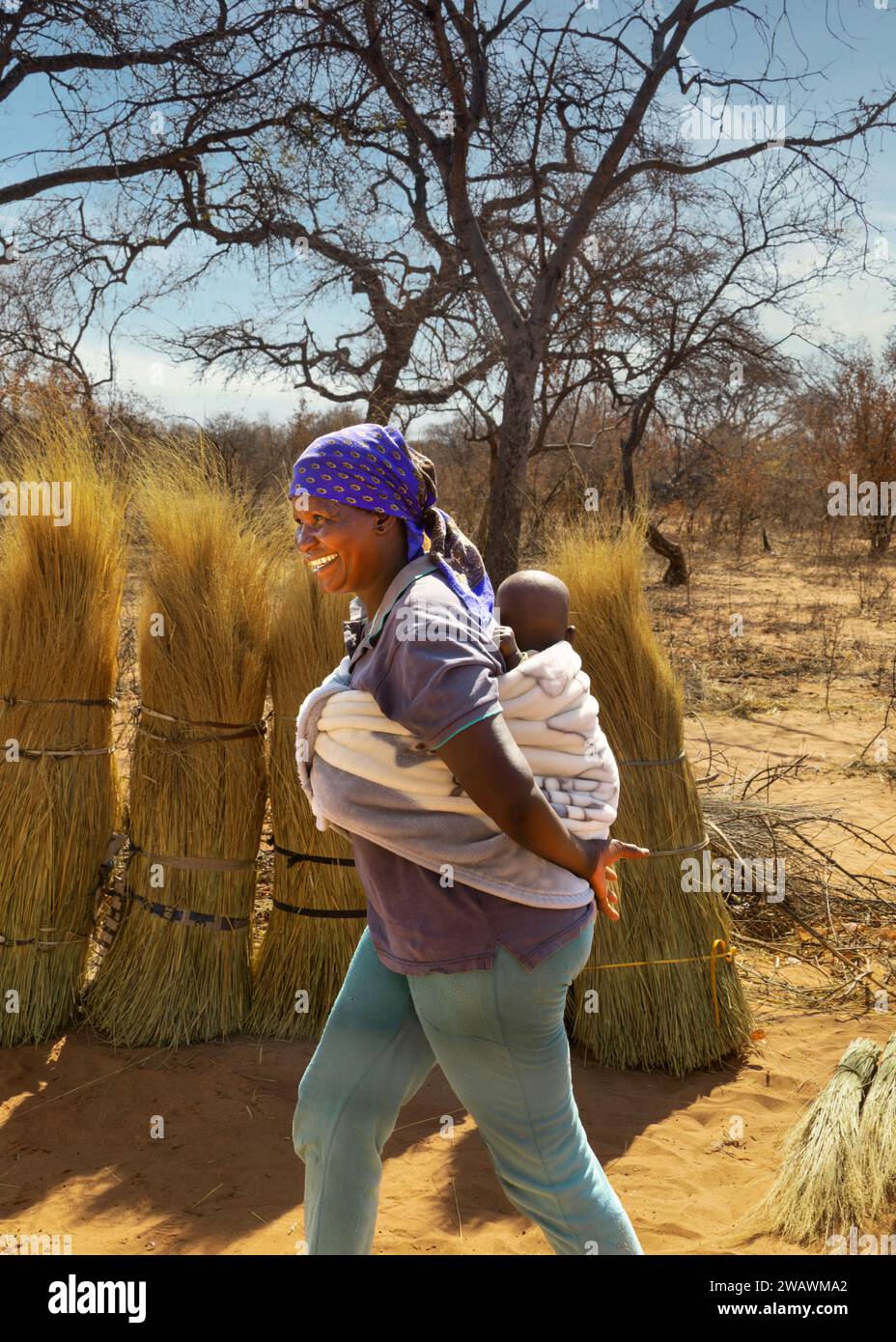 village life, African woman carry the baby in the back wrapped in a ...