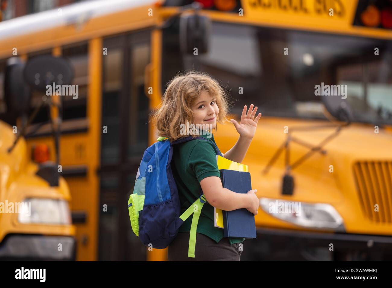 Pupil with backpack and book getting on the school bus. American School ...