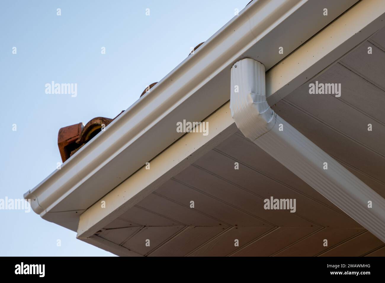 House corner with white wooden planks siding and roof with steel gutter ...