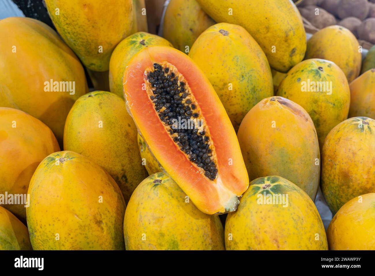 Sliced in half papaya fruit with more papayas in background Stock Photo ...