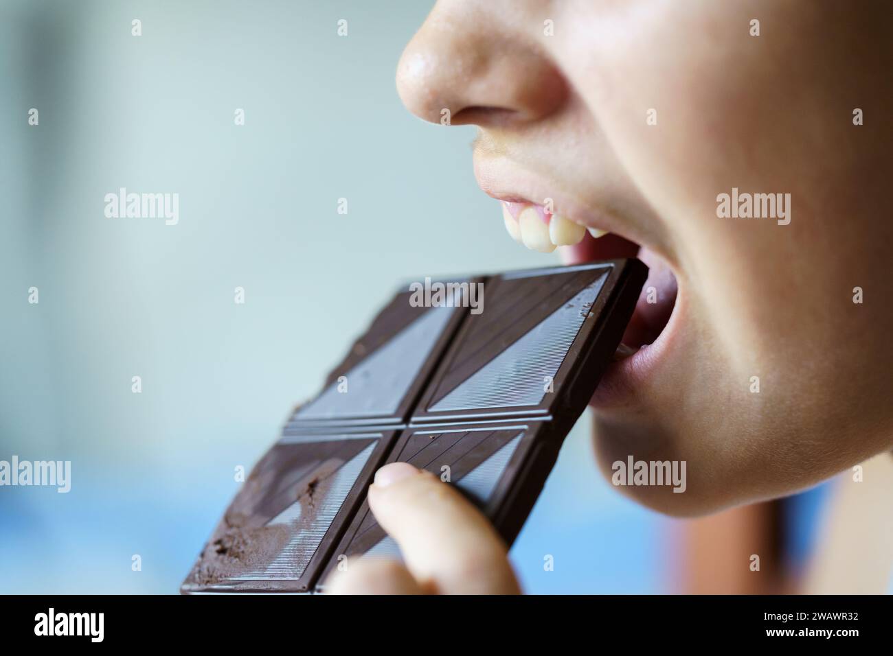 Anonymous girl with mouth open eating chocolate bar at home Stock Photo ...